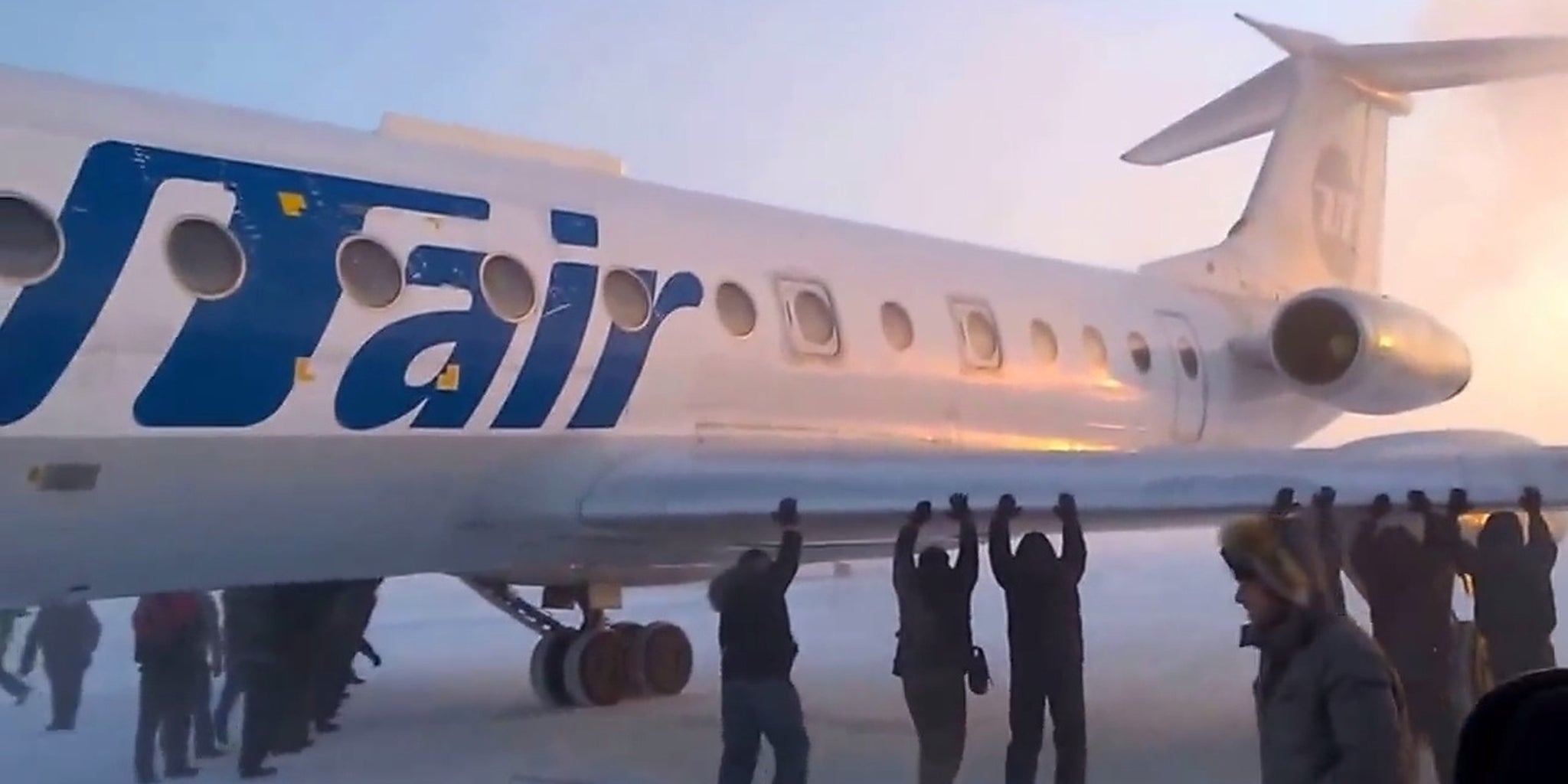 Russian travelers push their frozen plane free from the ice